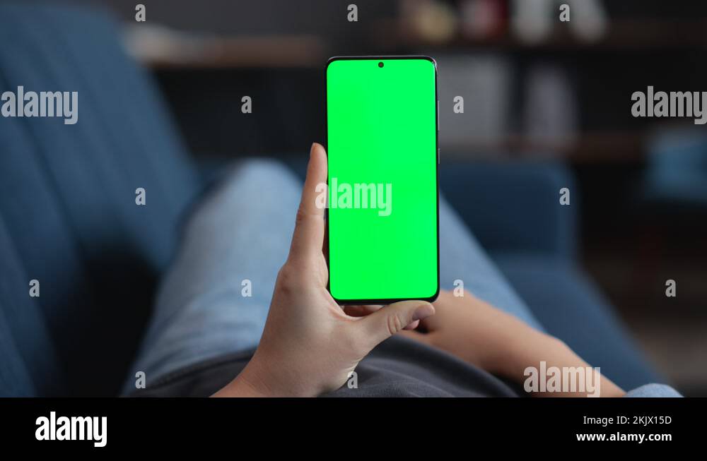 The woman is lying on a Coach in Living Room, holding Green Screen ...