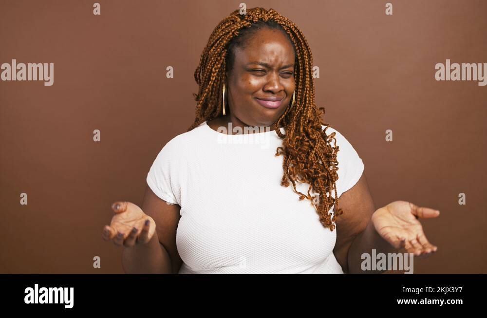 Emotional incomprehensible black woman shrugging shoulders and raising ...