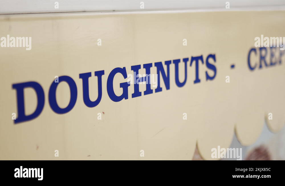 The blue words Doughnuts and Crepes on the signboard of a sweet snacks ...