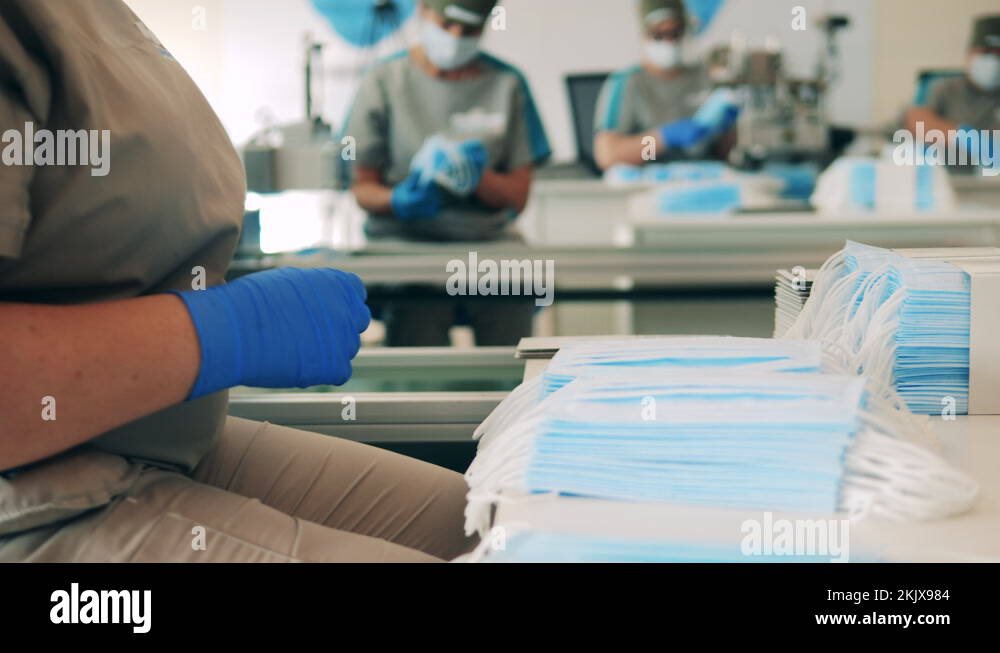 Batches of face masks are getting put together by a factory worker ...
