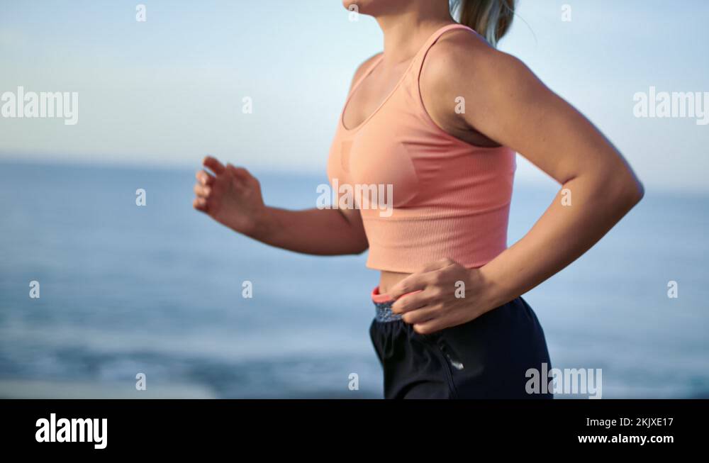 Closeup torso of muscular female athlete running on beach. Shot on RED ...