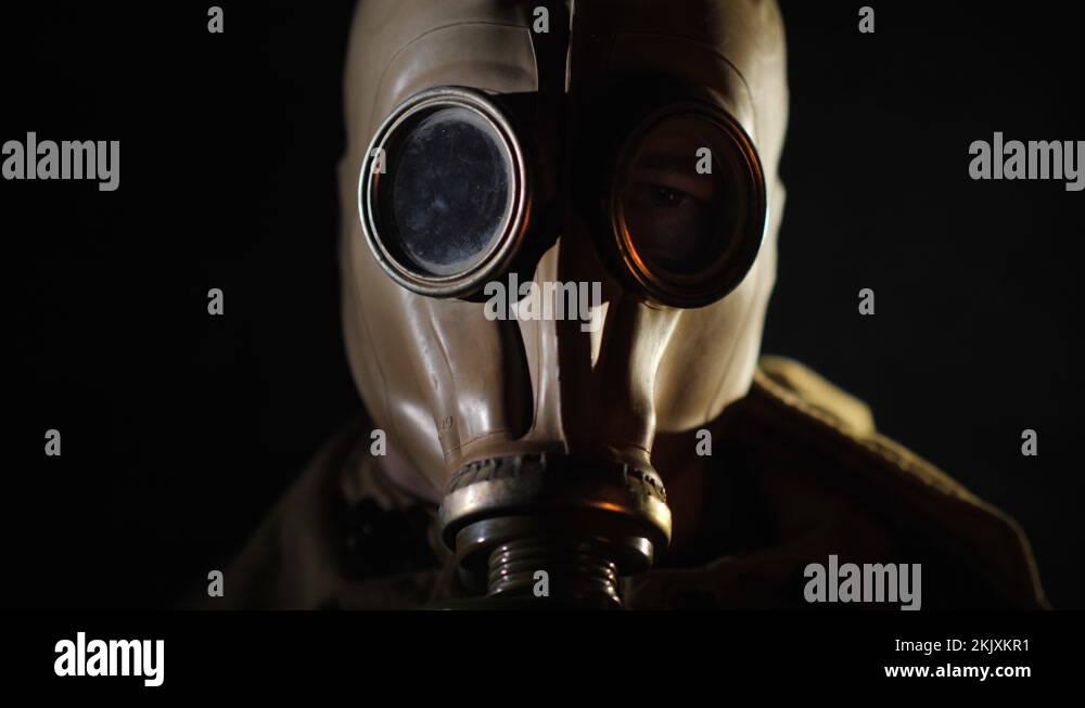 The gleams of the fire are reflected in the eye and gas mask of the man ...