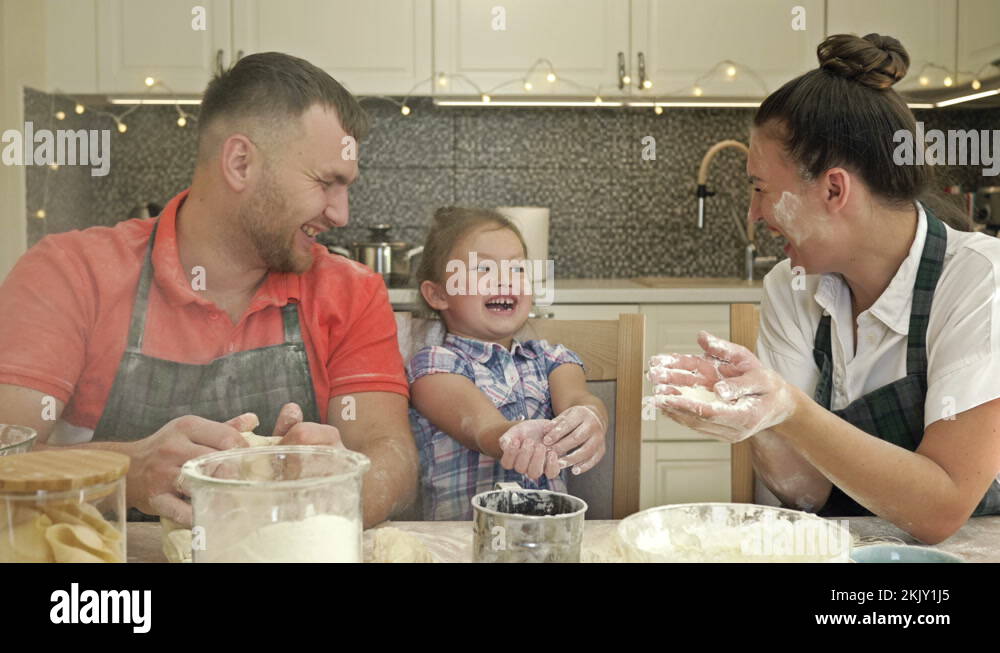Dad, mom and little daughter are cooking something in the kitchen ...