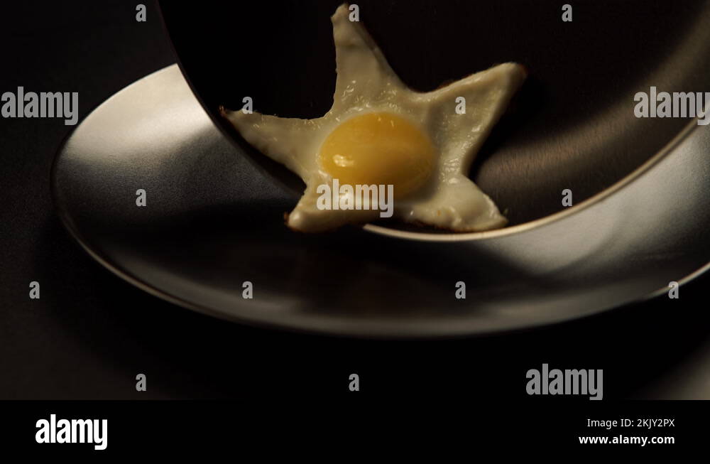 Taking out of a fried eggs in a form of a star from the pan to the dish ...