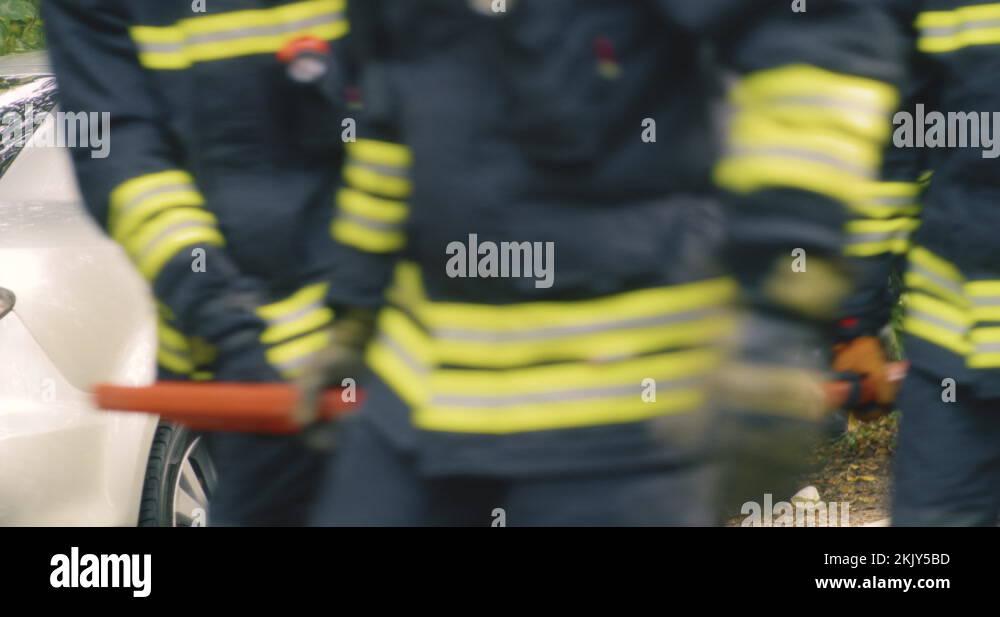 Anonymous firefighters extinguishing fire and carrying victim of car ...