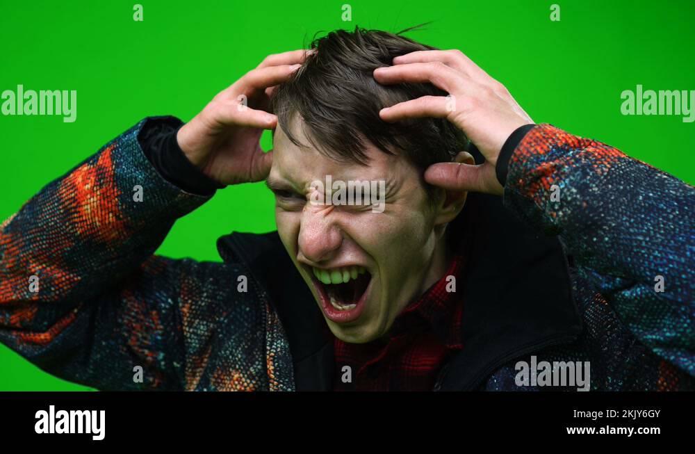 Man feeling headache holding his head with his hands in shock on green ...