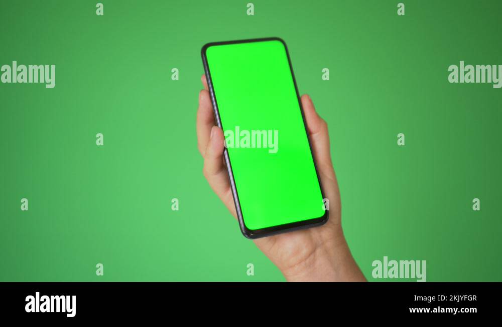 Woman hand holding the smartphone on green screen chroma key background ...