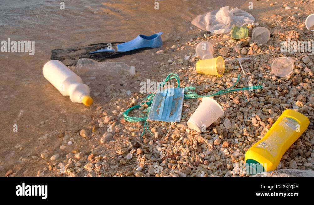 Disposable face masks and plastic debris on the beach in surf zone ...