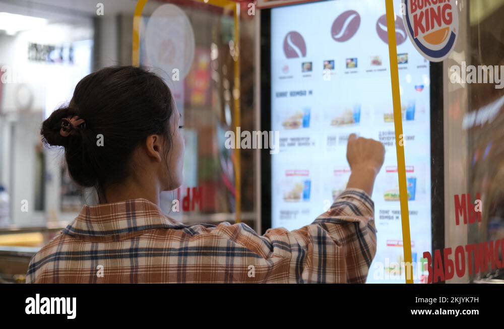 Woman types on fast food restaurant interactive order board ...