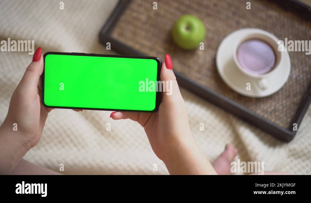 Back view over shoulder of young girl using smartphone with green ...