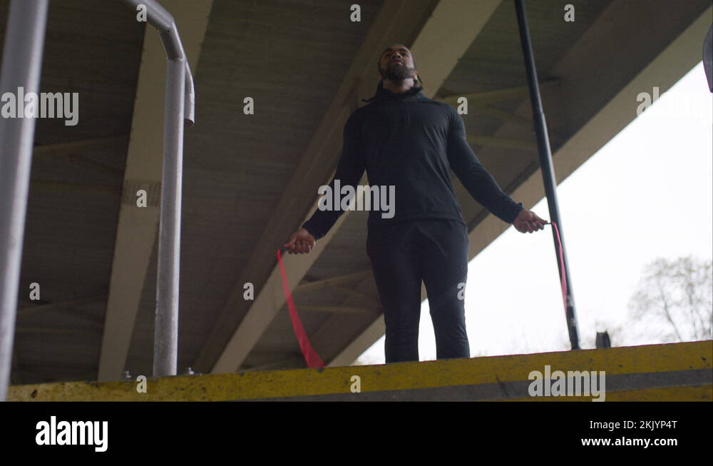 Camera moves from left to right as a man skips with a jump rope, in ...