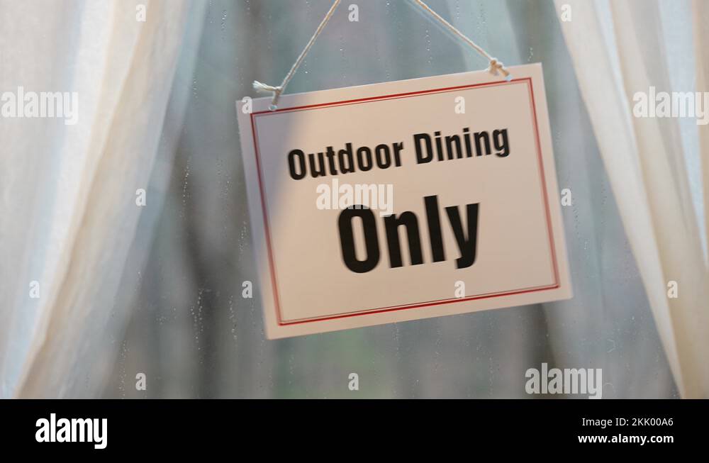 Outdoor Dining Only sign swinging in the window of store front display ...