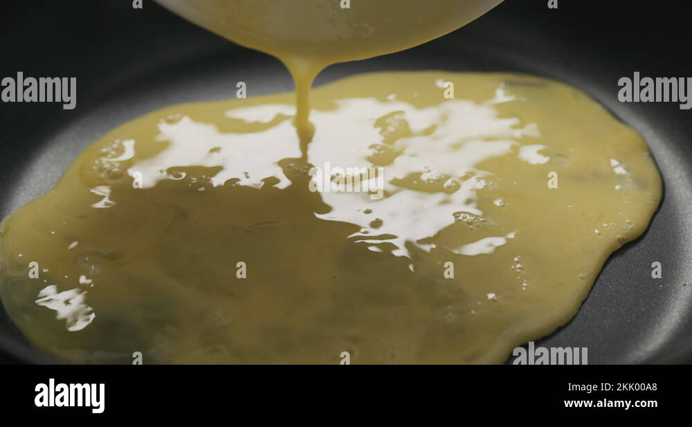 Slow motion making scrambled eggs, pour egg mixture on nonstick pan ...