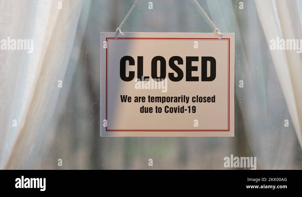 Closed sign swinging in the window of store front display in business ...