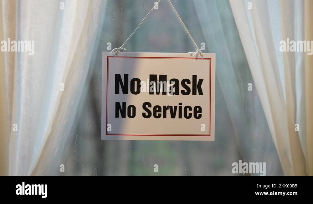No Mask No Service sign swinging in the window of store front display ...