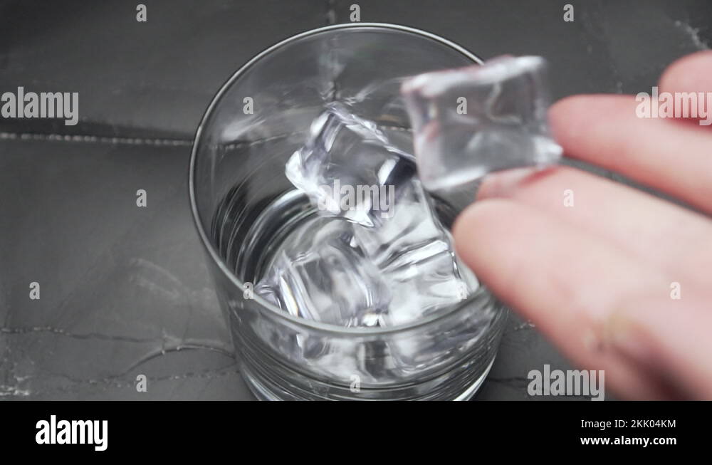 Falling ice cubes into a glass and pouring drinking pure water Stock ...