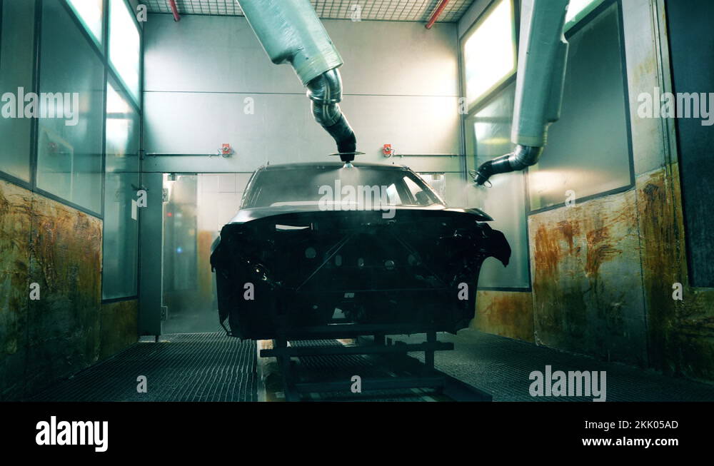 Robotic arms spray painting a vehicle body at a car manufacturing plant ...