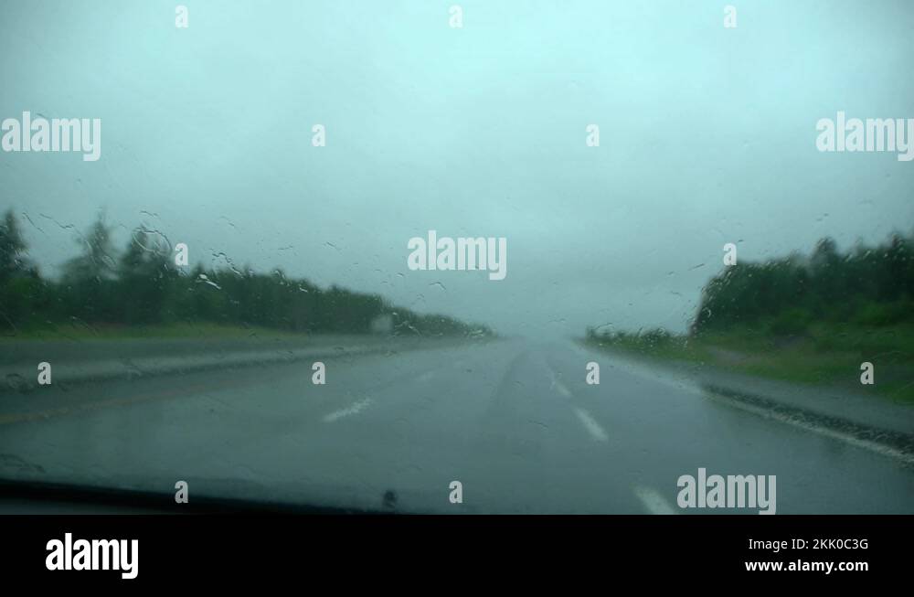 Car driving in rain storm empty highway road drivers point of view fast ...