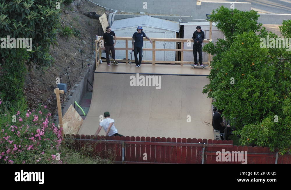 Skateboarder dropping-in on ramp and falling off board on backyard ramp ...