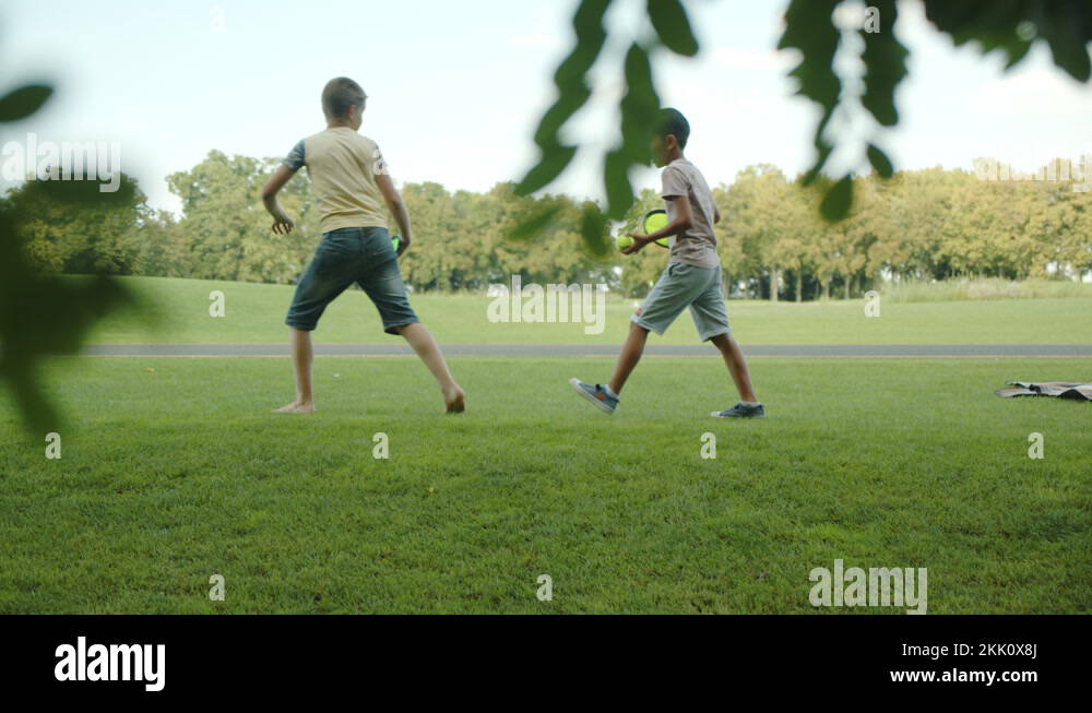 Two children throw and catch a ball in the park, Asian and Caucasian ...