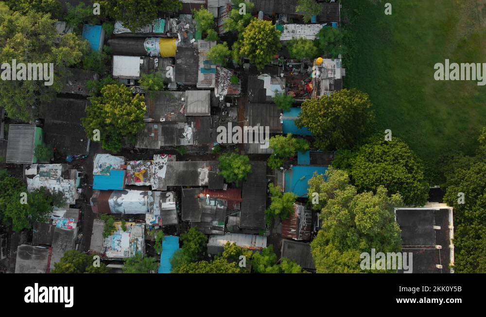 Top down look at slum in India, ramshackle homes and trees standing ...