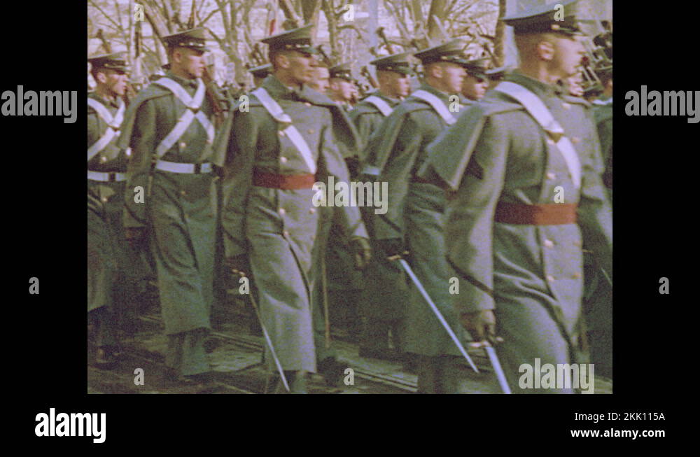 1960s: Soldiers march in military uniforms carrying swords. Color guard ...