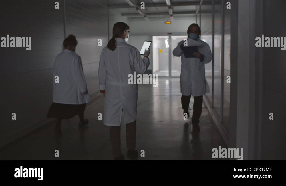 Back view of senior woman scientist walking in laboratory corridor and ...
