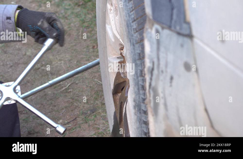 Man unscrews the wheel nuts for replacement with a wrench Stock Video ...