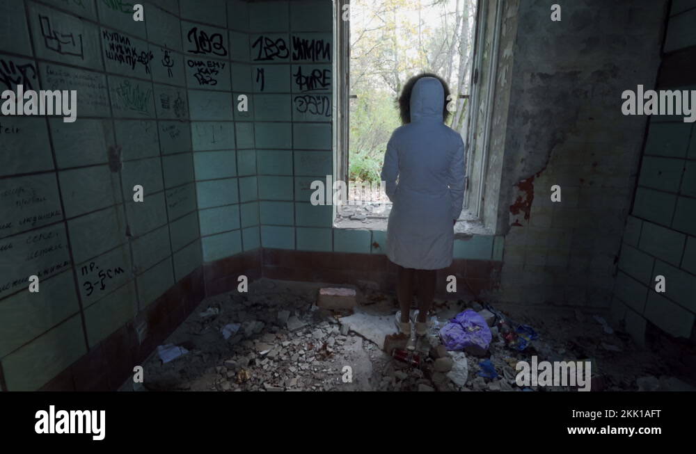 Woman looking through window frame of old destroyed house, stone ...