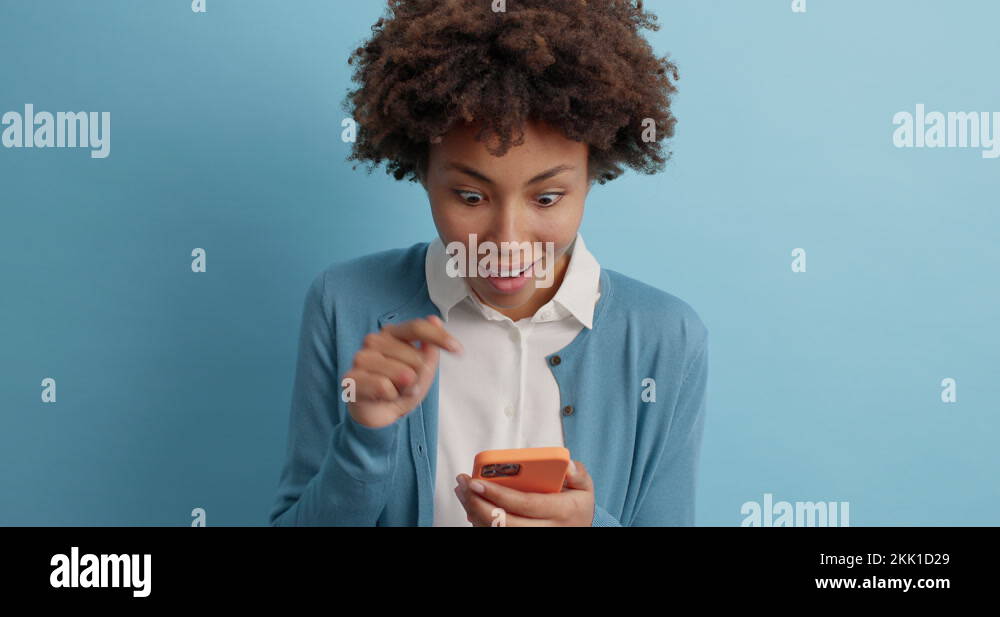 Young Shocked Curly Haired Young Woman Feels Surpsied Looks With