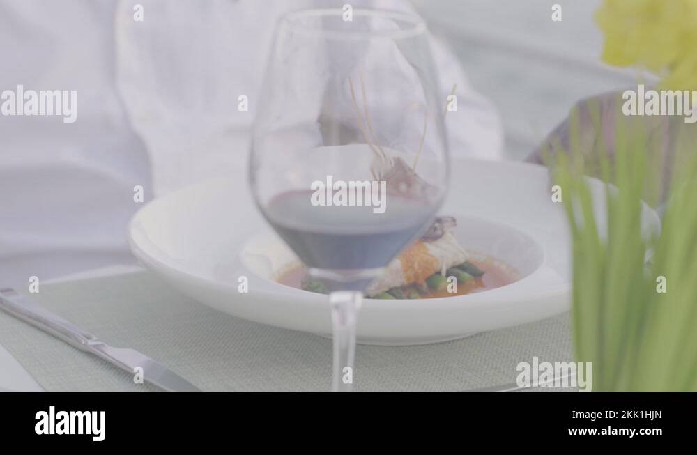 A waiter is serving a main plate to a customer of a restaurant. There ...