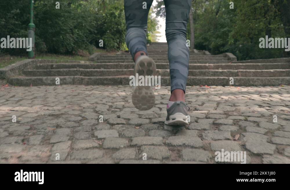 Person running up stairs in a park. Girls feet exercising low-angle ...