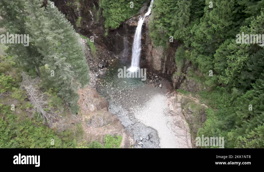 Water cascades over a hidden grotto nestled in lush evergreen forest ...