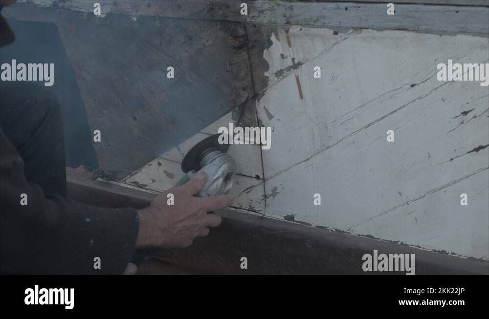 Cutting out rotten mahogany planking with angle grinder on eighty year ...