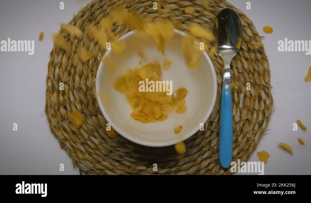Corn flakes cereals falling into a bowl. Top view, slow motion shot ...