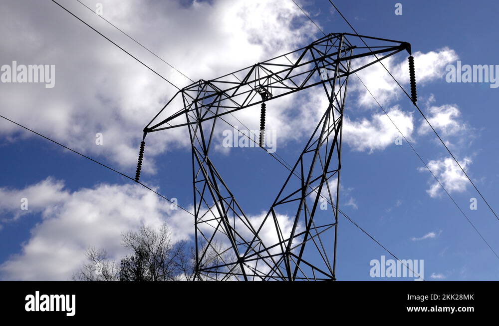 Electrical pylon with insulators and transmission lines. Light clouds ...