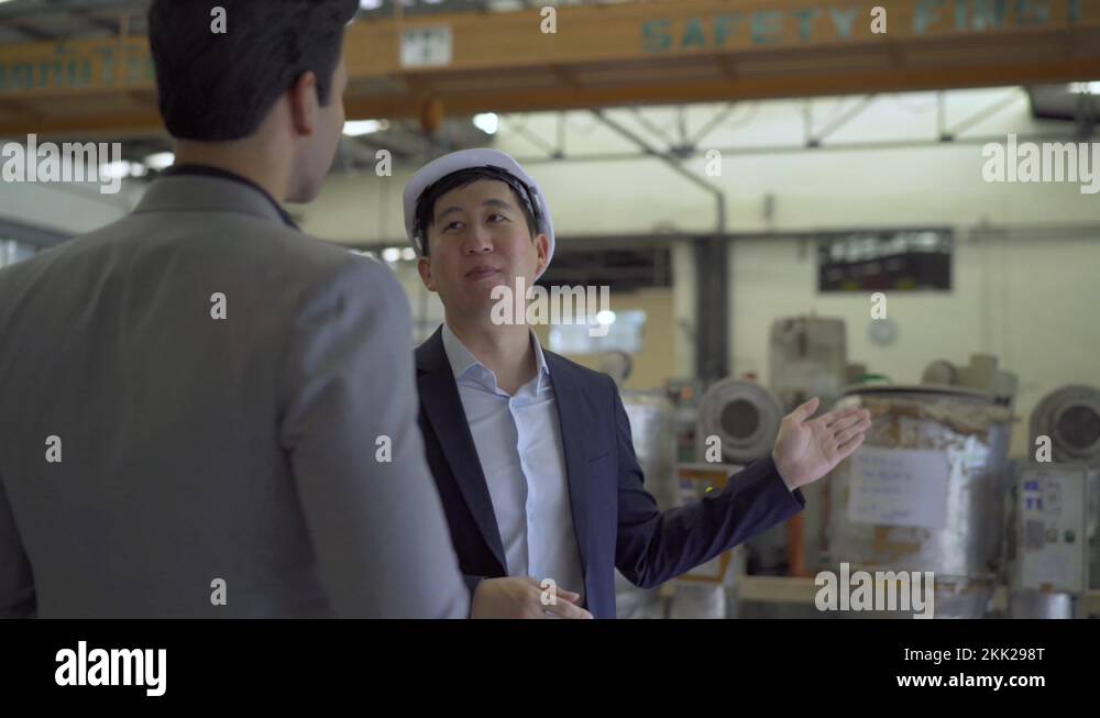 30s young Asian businessman in formal suit and hard hat showing foreign ...