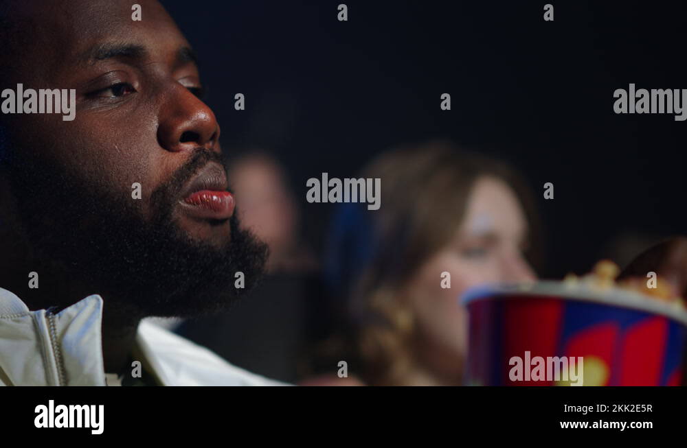 African man eating popcorn in movie theater. Afro guy looking film in cinema Stock Video Footage ...