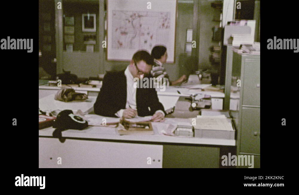 1970s: Newsroom, people sit at desks, flip through papers, take notes ...