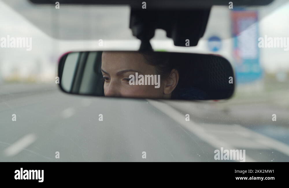 woman sitting behind the wheel driving car female face in rear view ...