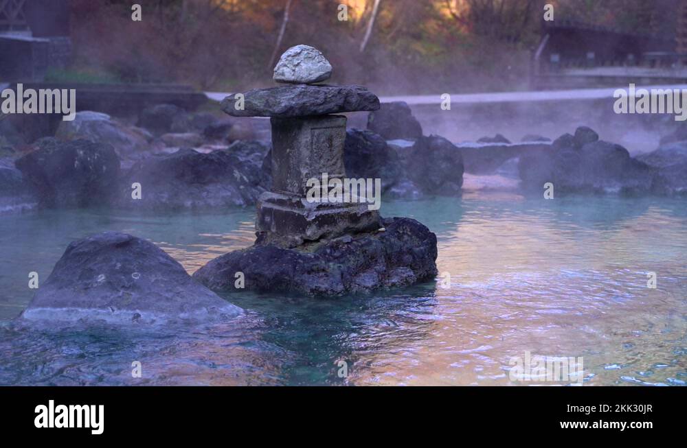 Stone pillar inside natural Japanese hot spring with steaming hot water ...