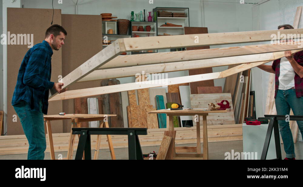 Young carpenters build a solid wood wall in a carpentry workshop. The ...