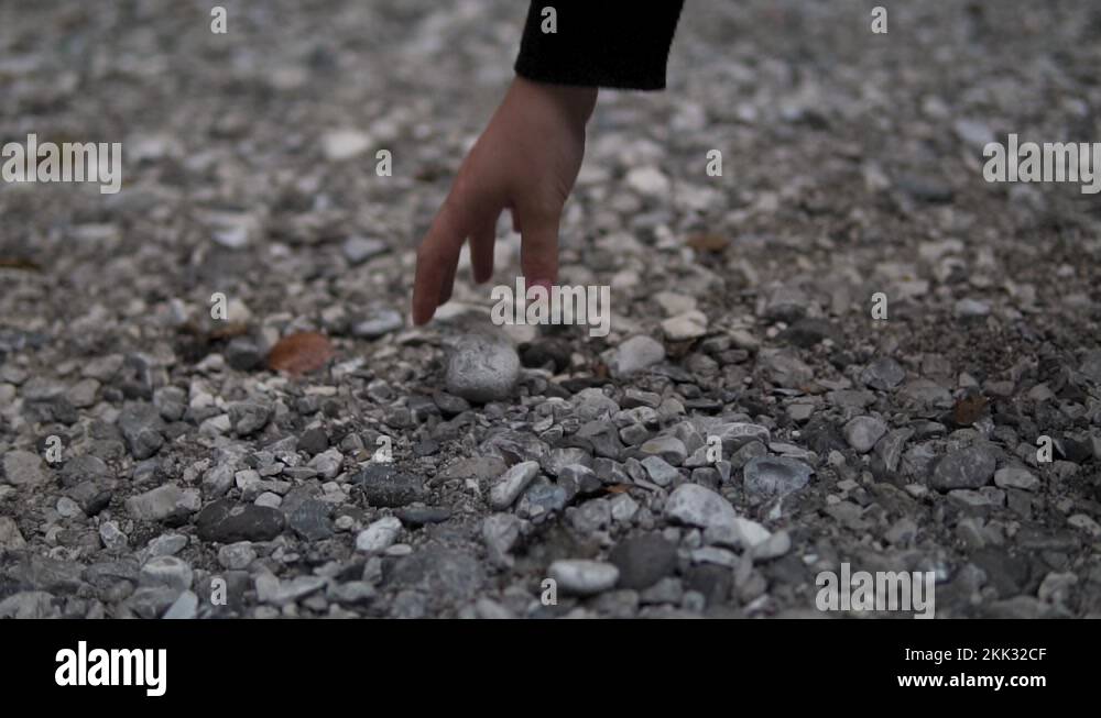 Close up on female hand picking up pebble from the ground in slow ...