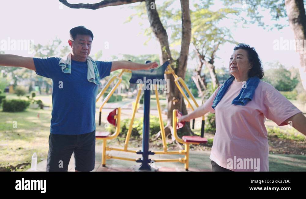 Asia senior, warm up exercise together before work out inside the park ...