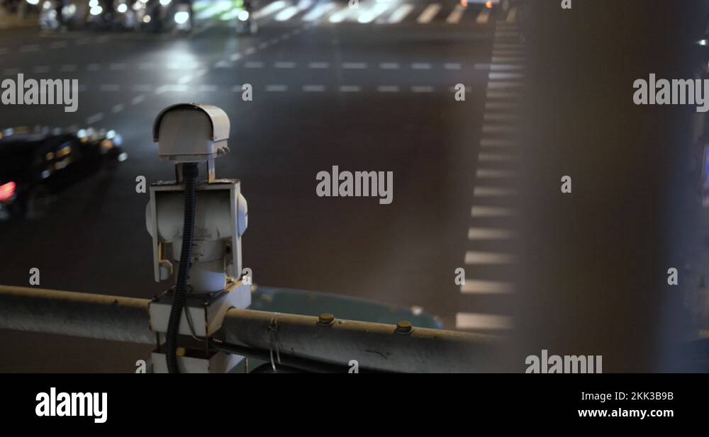 A security CCTV camera at pedestrian crossing on busy street at night ...
