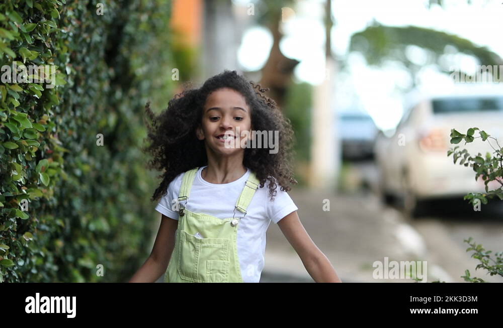 Happy little girl running outside in sidewalk. Mixed race black child ...