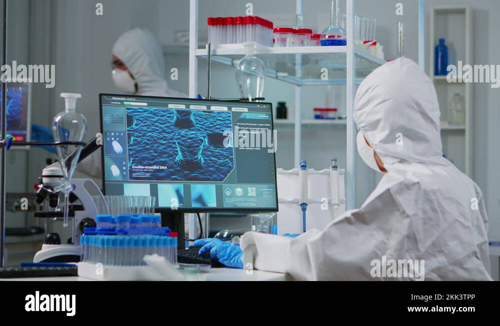 Chemist in ppe suit typing on computer checking virus development Stock ...
