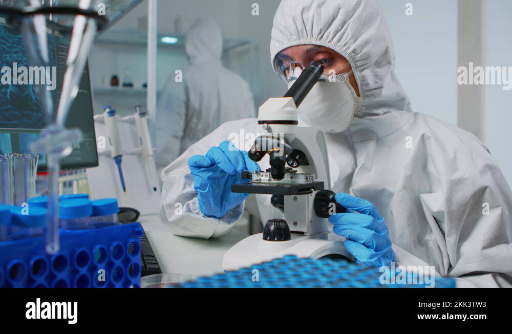 Scientist wearing ppe suit looking at samples under microscope Stock ...