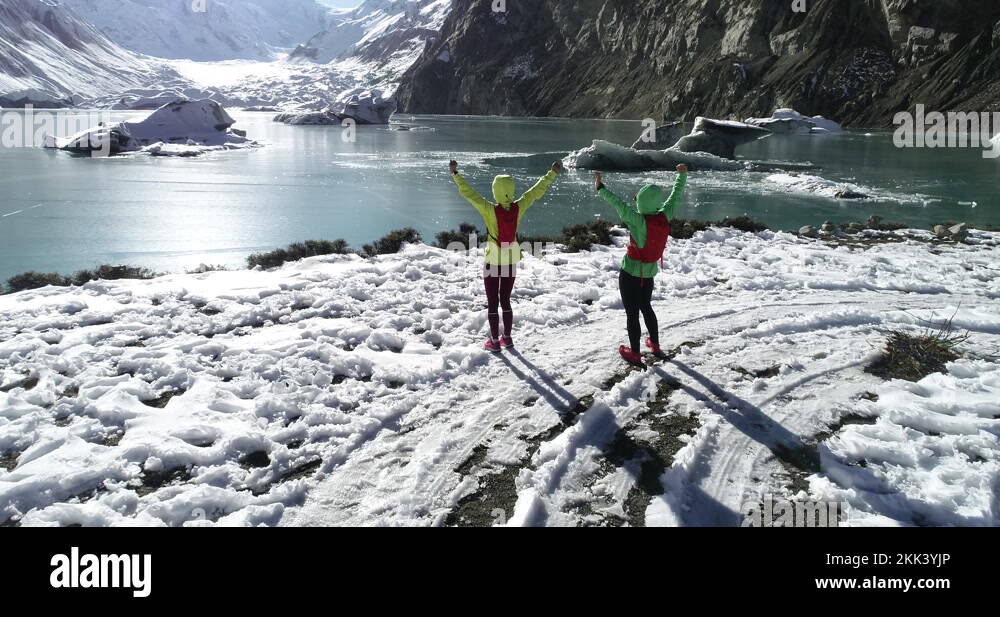 Two women trail runners open arms to the frozen glacier lagoon Stock ...