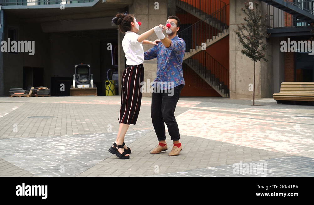 Man and woman clowns in costumes are meeting talking then dancing ...